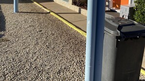 Um motel com galeria coberta, quartos individuais com aparelhos de ar condicionado e estacionamento com calçamento de brita.