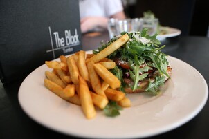 Um prato com sanduíche e batatas fritas sobre uma mesa, com uma placa que diz "The Black".