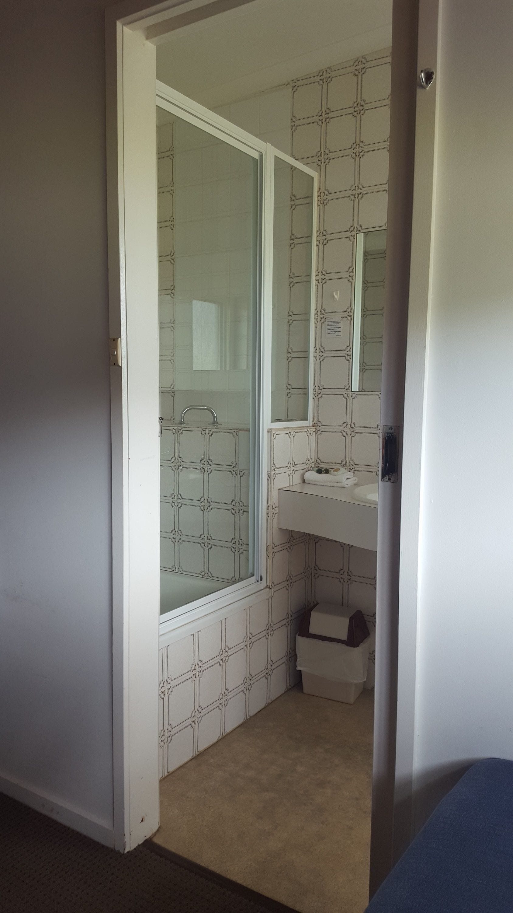 Uma casa de banho pequena com chuveiro, lavatório e espelho.