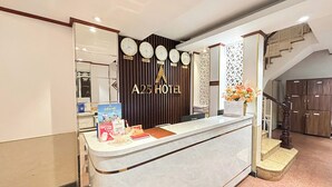 Uma receção com design moderno, um relógio e um sinal com o nome A25 Hotel.
