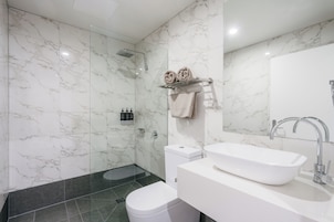 Uma casa de banho moderna com cabine de chuveiro em vidro, lavatório branco e sanita.