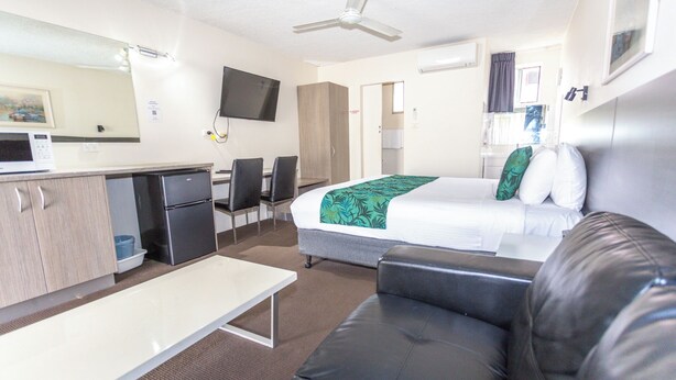 Quarto de hotel com cama, escrivaninha, cadeira, televisão, micro-ondas e frigorífico.