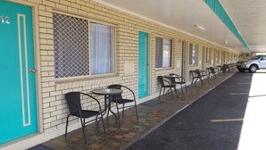 Um motel com portas numeradas, área de estar externa e estacionamento.