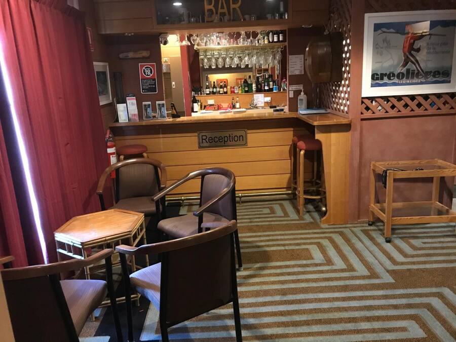 Uma área de bar com balcão de recepção, balcão do bar e disposição de assentos.