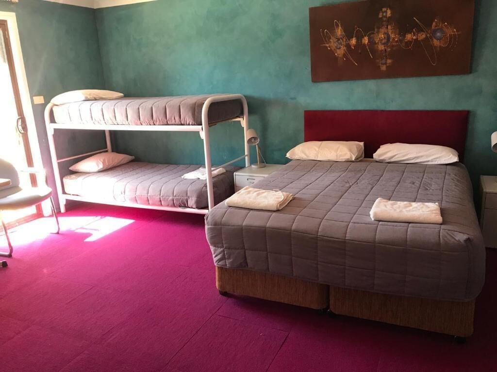 Quarto com beliches, cabeceira vermelha e um quadro na parede.