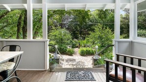 Alpendre coberto com vista para um jardim, uma escadaria de pedra e um deck de madeira.