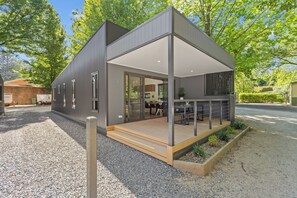 Uma casa moderna com varanda coberta, entrada de automóveis com cascalho e jardim cercado.