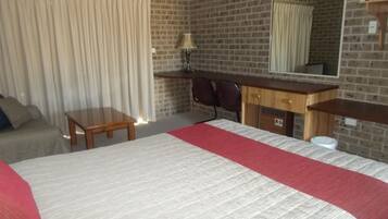Quarto de hotel com uma cama grande, uma escrivaninha, uma cadeira e um espelho.