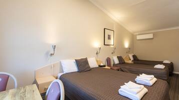 Quarto de hotel com duas camas, uma escrivaninha e uma cadeira.
