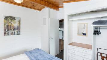Um quarto com cama, cômoda, espelho e um quadro na parede.