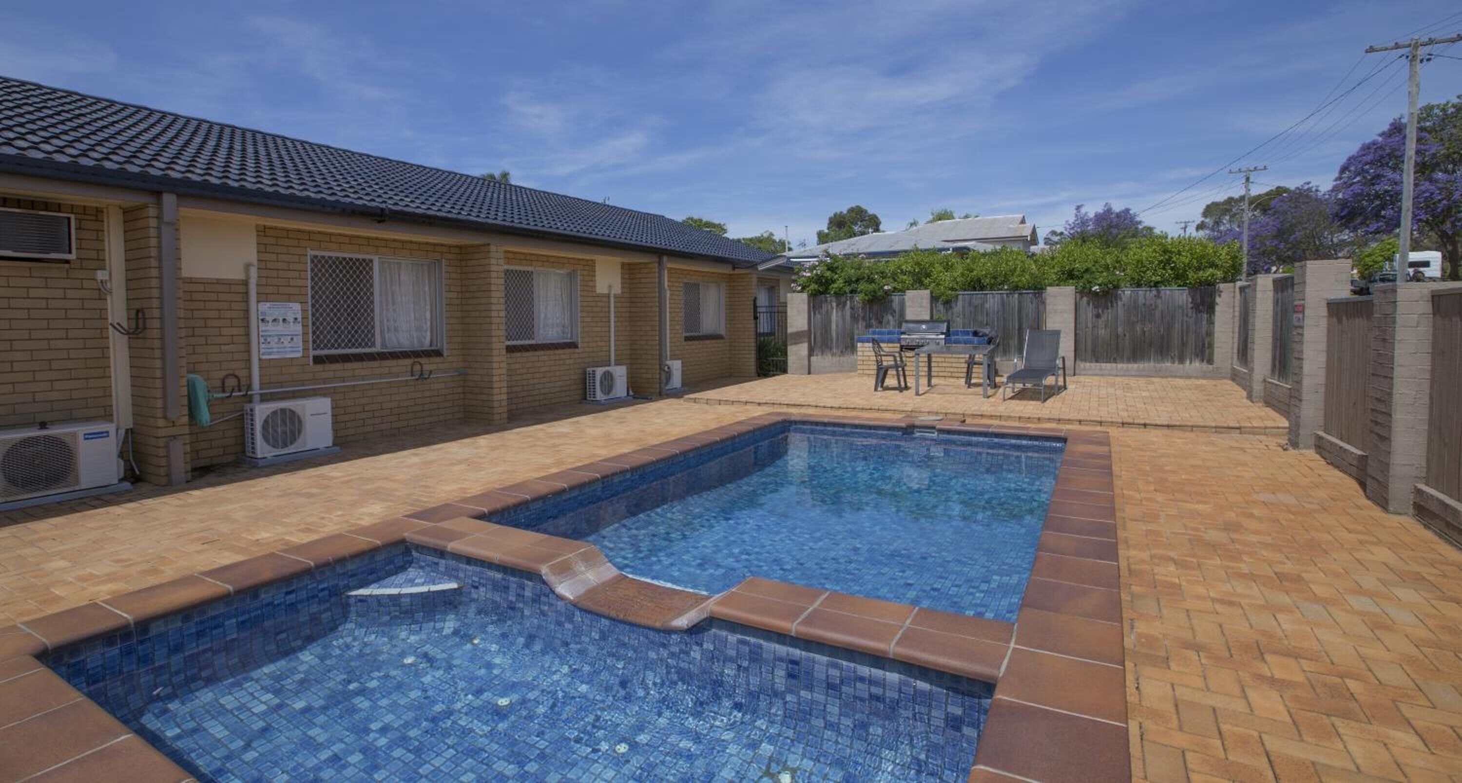 Quintal residencial com piscina, espaço para churrasco e jardim cercado.