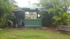 Um gazebo com uma placa indicando "Camp Kitchen" e uma placa com a inscrição "Emergency Assembly Area".