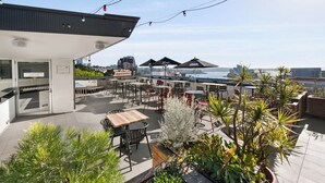 Terraço no telhado com área de estar ao ar livre, vista da cidade e um edifício com design moderno.