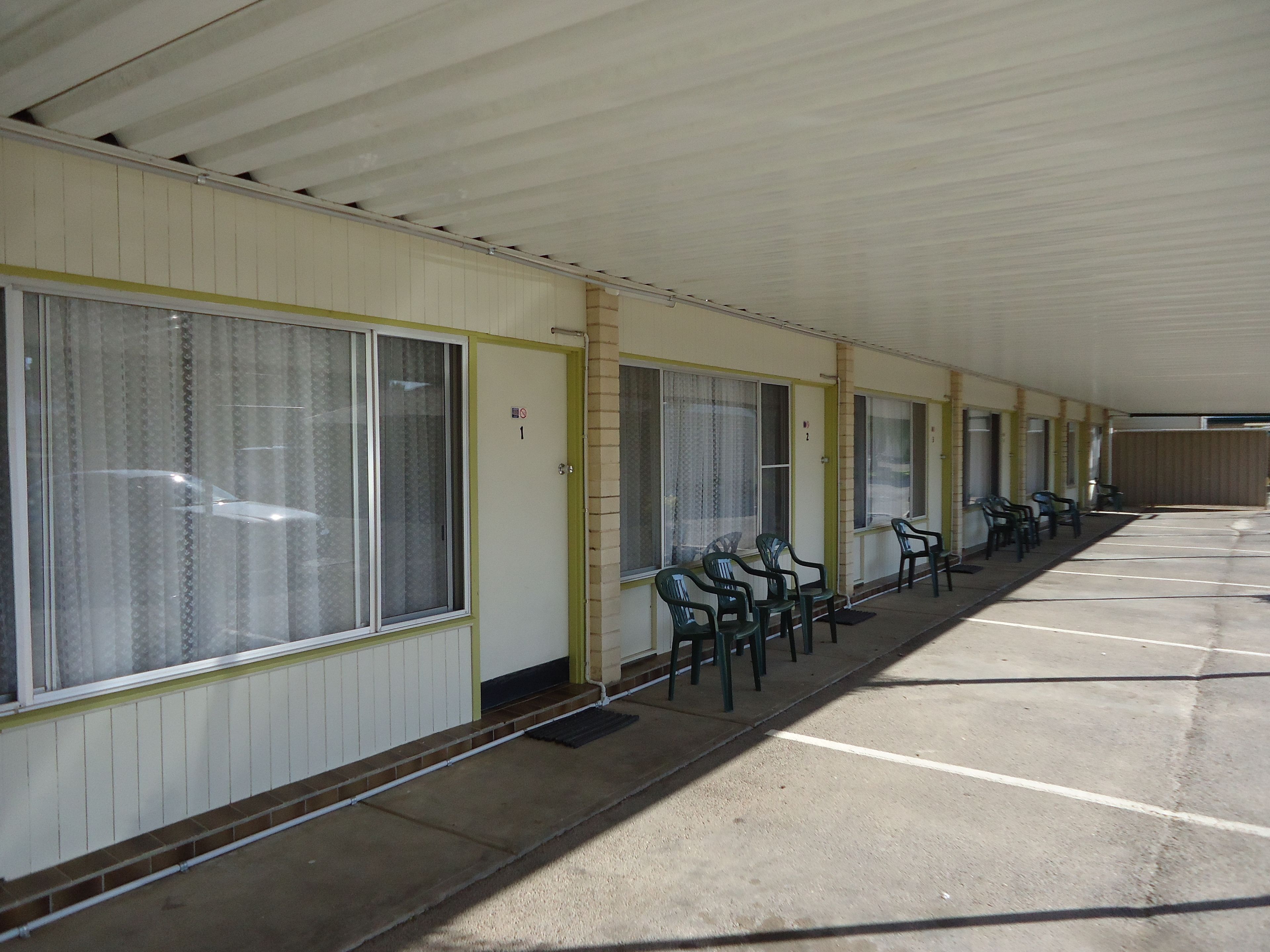 Um motel com uma fileira de quartos individuais, cada um com janela e porta.