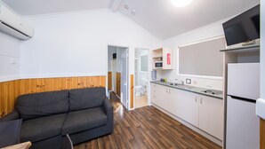 Um espaço compacto para viver, com sofá, cozinha compacta e porta de acesso a um banheiro.