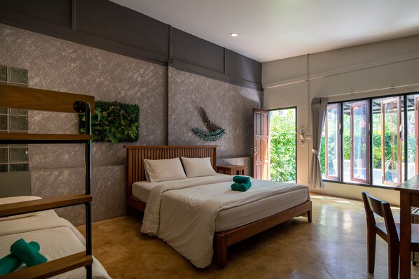 Quarto moderno com cama de madeira, mesinha de cabeceira e vista para o verde pela janela.