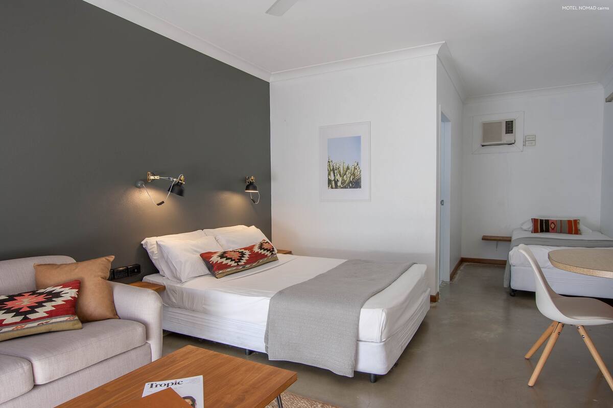 Quarto de hotel moderno com cama, sofá, escrivaninha e cadeira.