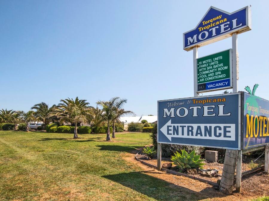 Placa de motel com mensagem de boas-vindas, indicando 18 unidades de motel, apartamentos familiares, banheiras de hidromassagem, salão comunitário, piscina e ar condicionado.