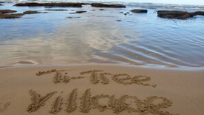 Uma praia com as palavras "T-Tree Village" escritas na areia.