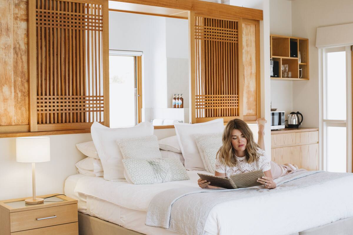Quarto com cama, mesa de cabeceira e luminária.