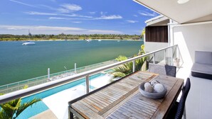 Uma varanda com vista para o mar, uma piscina e uma área de refeições com mobiliário de exterior.