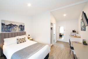 Quarto moderno com uma cama grande, mesas de cabeceira e um quadro na parede.