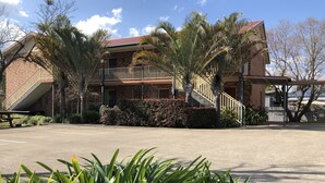 Um edifício com fachada de tijolos, uma varanda e uma escadaria que leva a um andar superior.