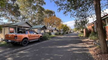 Uma rua residencial com casas, uma caminhonete laranja estacionada e árvores.