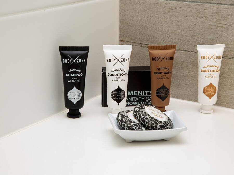 Quatro produtos de cuidados para o corpo da Body Zone sobre uma superfície branca.