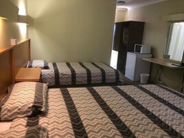 Quarto de hotel com duas camas, uma escrivaninha, micro-ondas e um refrigerador pequeno.