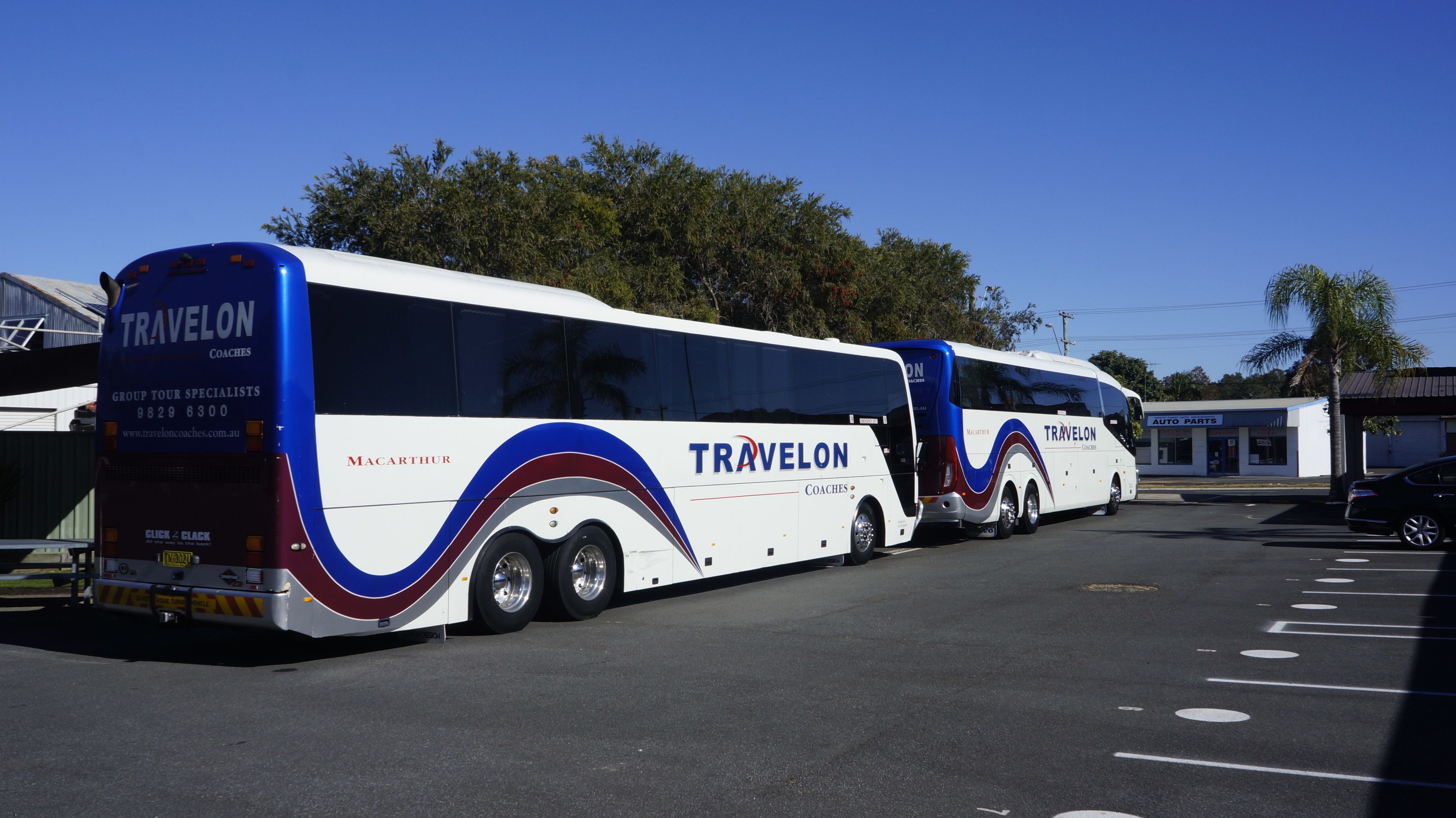 Um ônibus grande branco com detalhes em azul e vermelho estacionado em um estacionamento.