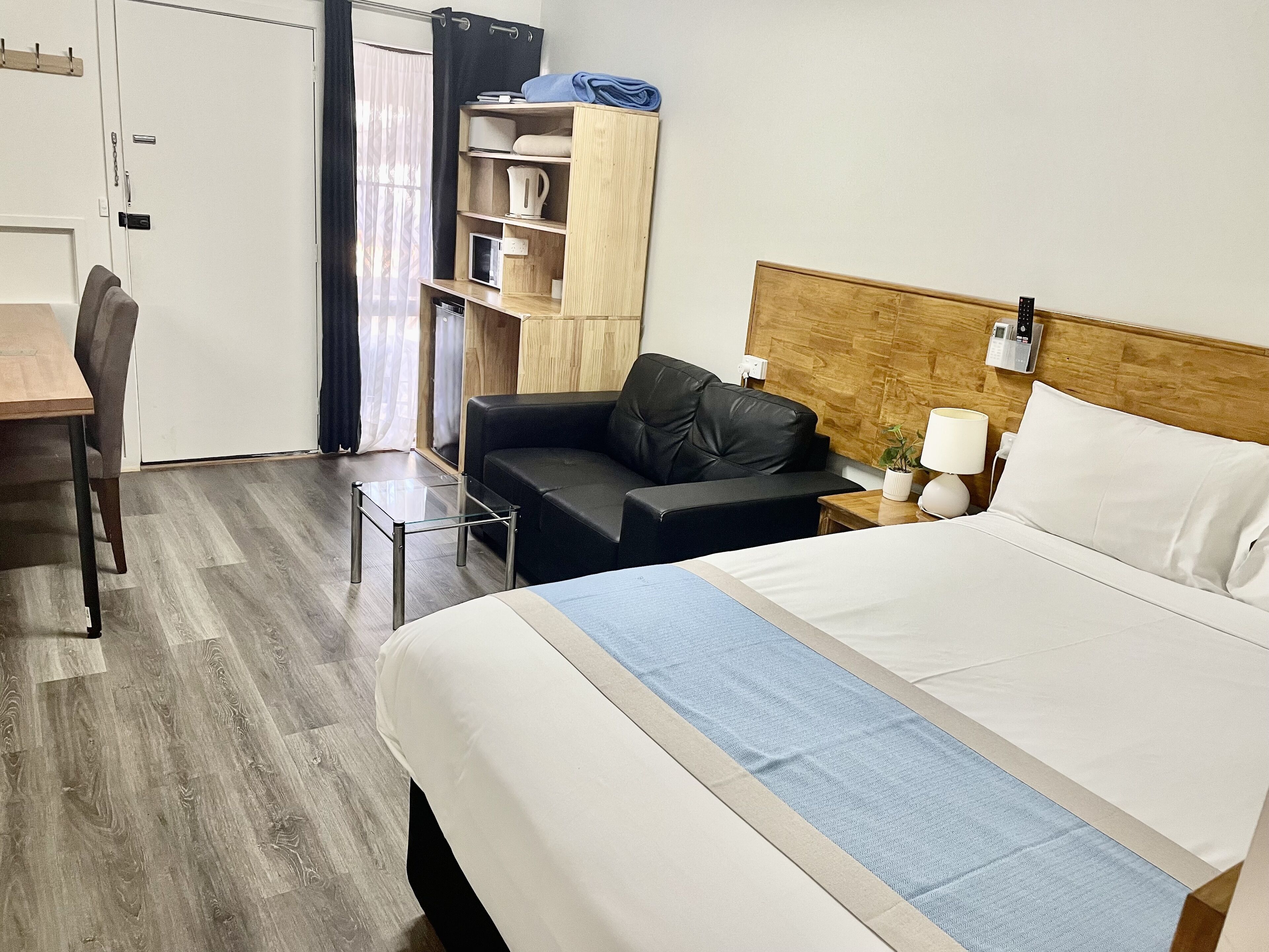 Quarto de hotel com cama, sofá, escrivaninha e uma pequena mesa.