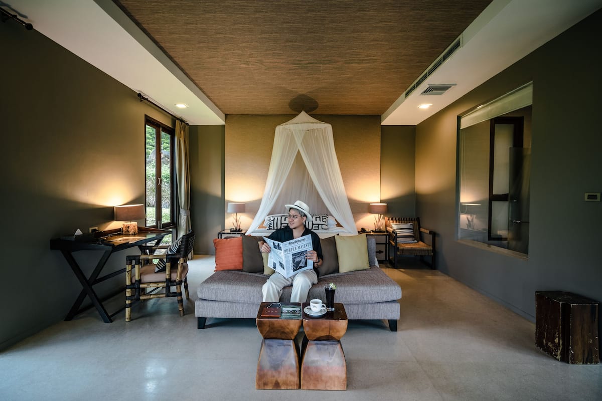 Uma sala de estar moderna com sofá, mesa de centro e um espaço de leitura com poltrona e luminária.