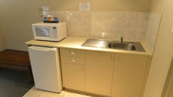 Uma cozinha compacta equipada com micro-ondas, pia e um refrigerador pequeno.
