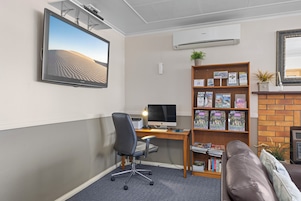 Um espaço de escritório moderno com uma mesa, computador, estante e uma grande fotografia emoldurada.