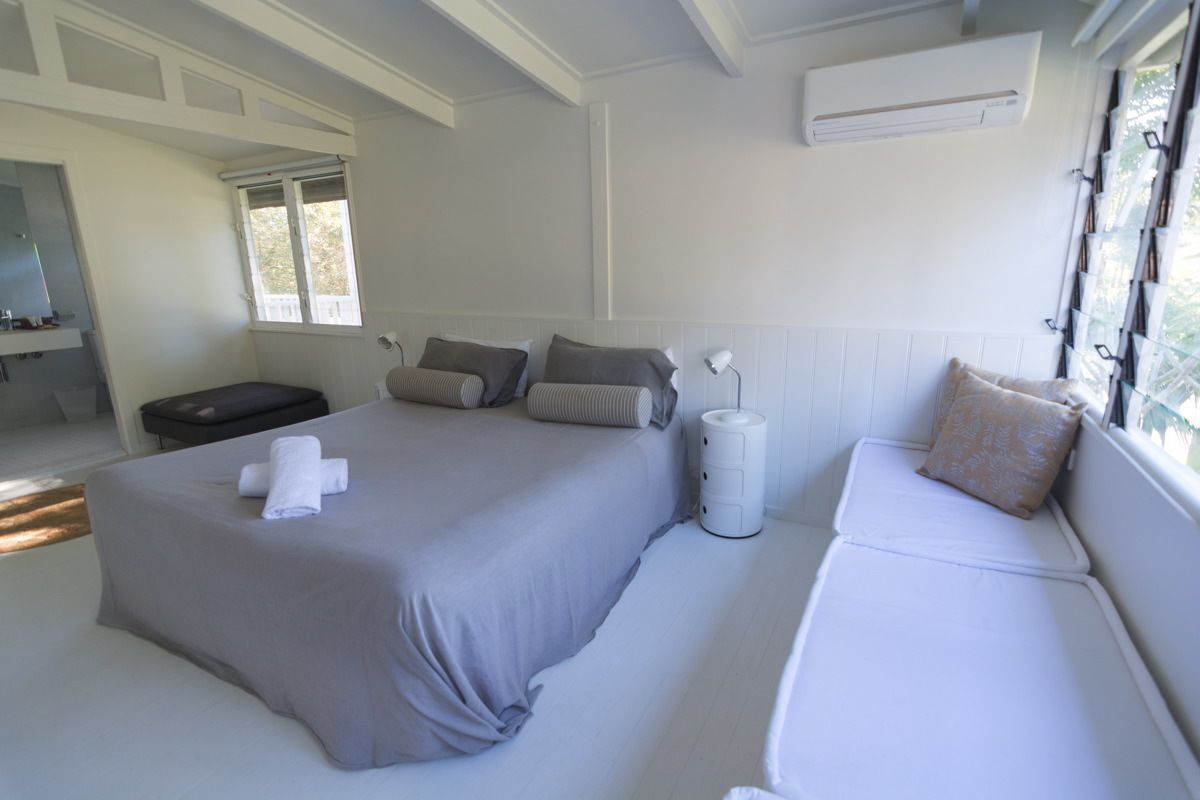Quarto com uma cama grande, mesas de cabeceira, uma janela e um ar condicionado.