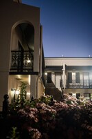 Um edifício com varanda, escadaria e portão.