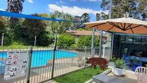 Piscina com área cercada, espaço de estar coberto e placa com regras de comportamento na piscina.