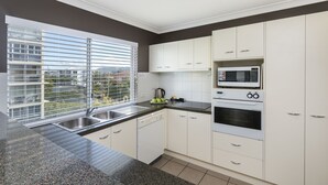 Uma cozinha moderna com armários brancos, bancada de granito, micro-ondas embutido e lava-louças.
