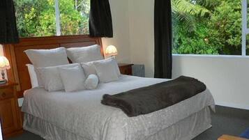 Quarto com uma cama grande, duas mesas de cabeceira e uma janela com cortinas.