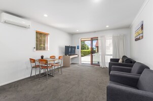 Quarto moderno com área de refeições, televisão de tela plana e sofá.