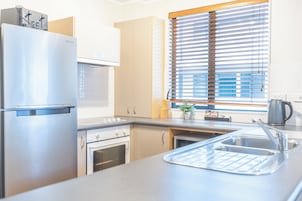 Uma cozinha moderna com eletrodomésticos de aço inoxidável, forno embutido e janela com persianas.