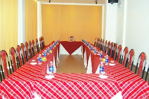 Uma sala de conferência com uma mesa comprida, cadeiras e um pódio.