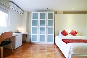 Um quarto com uma cama, uma escrivaninha e um guarda-roupa.