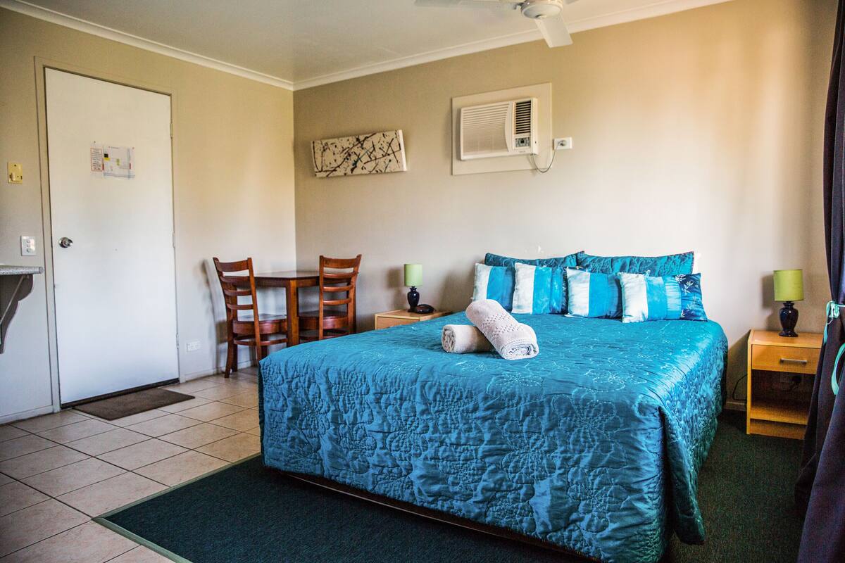 Quarto de hotel com cama, escrivaninha e cadeira.