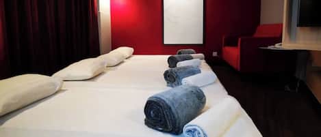 Quarto de hotel com uma cama grande, paredes vermelhas e cortina vermelha.