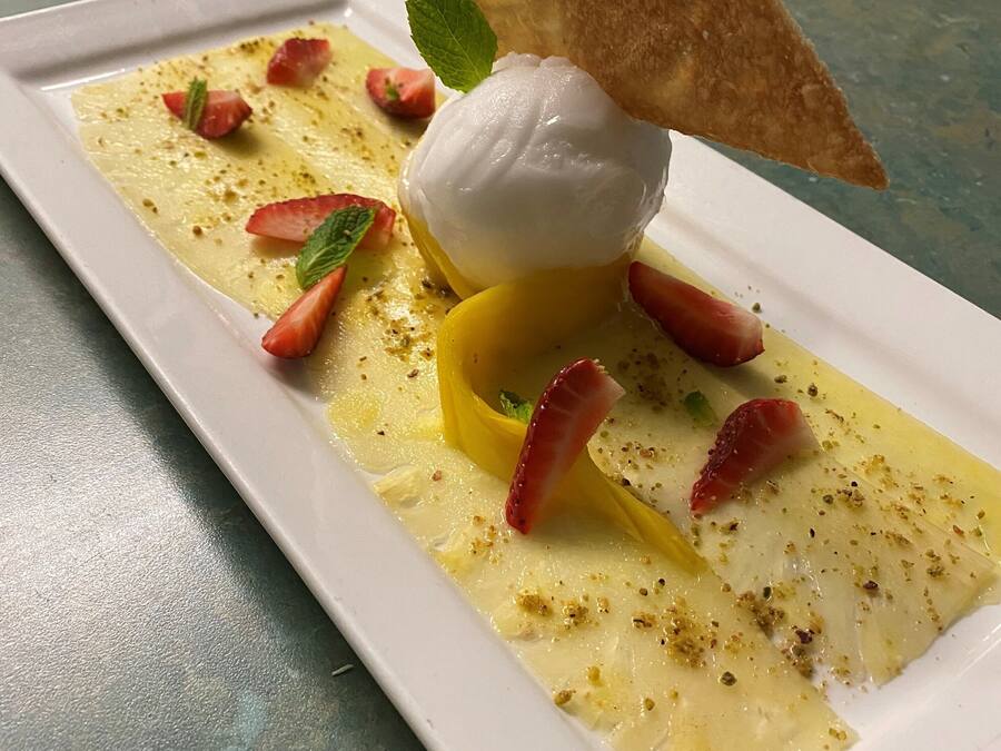 Um prato de sobremesa com uma bola de sorvete, morangos e uma fatia de torrada.