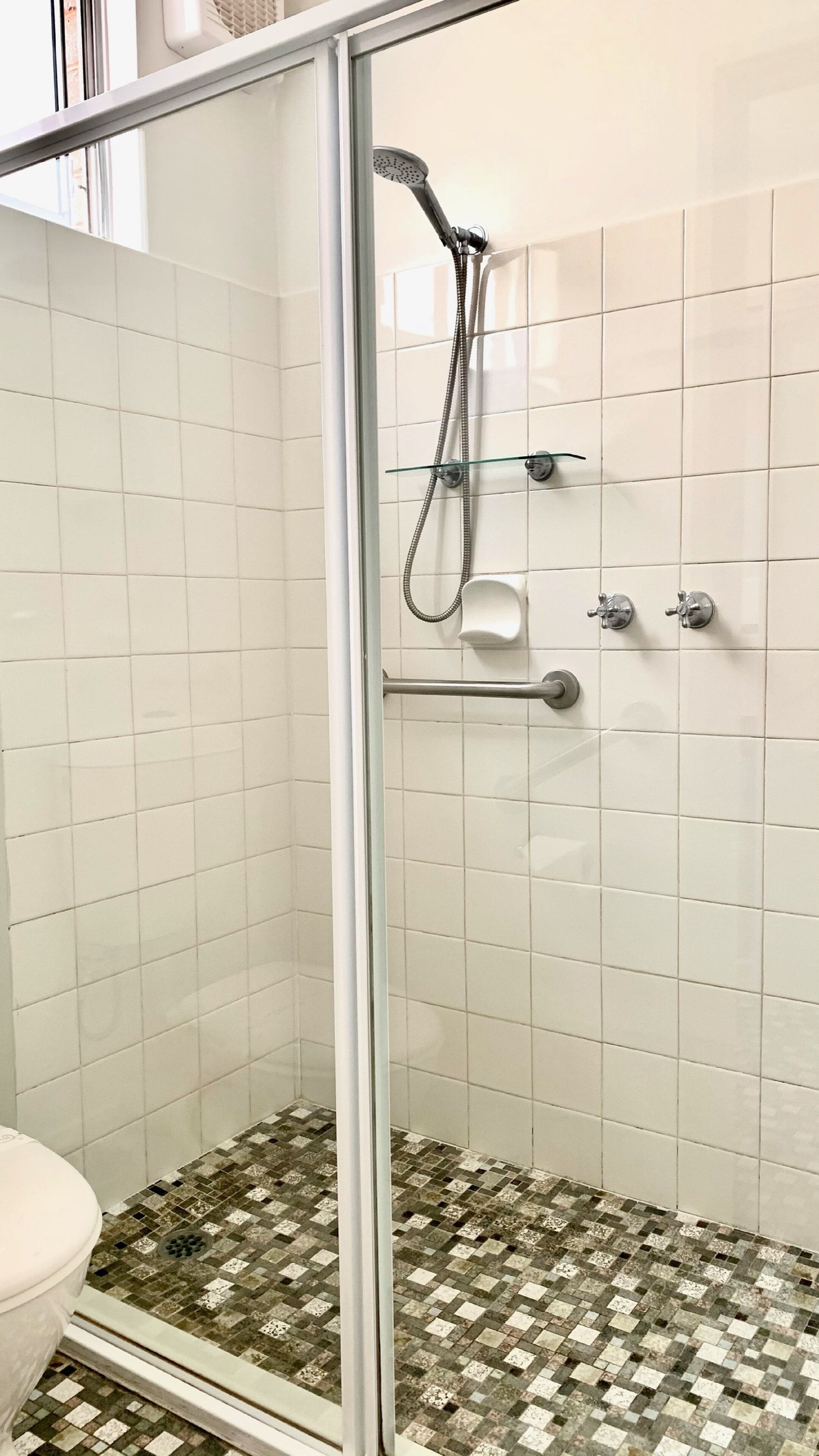 Um chuveiro envidraçado com três duchas manuais.