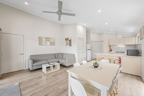 Cozinha moderna com armários brancos, micro-ondas e área de refeições com mesa e cadeiras.