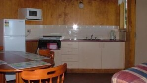 Uma cozinha compacta com geladeira, fogão, micro-ondas e pia.